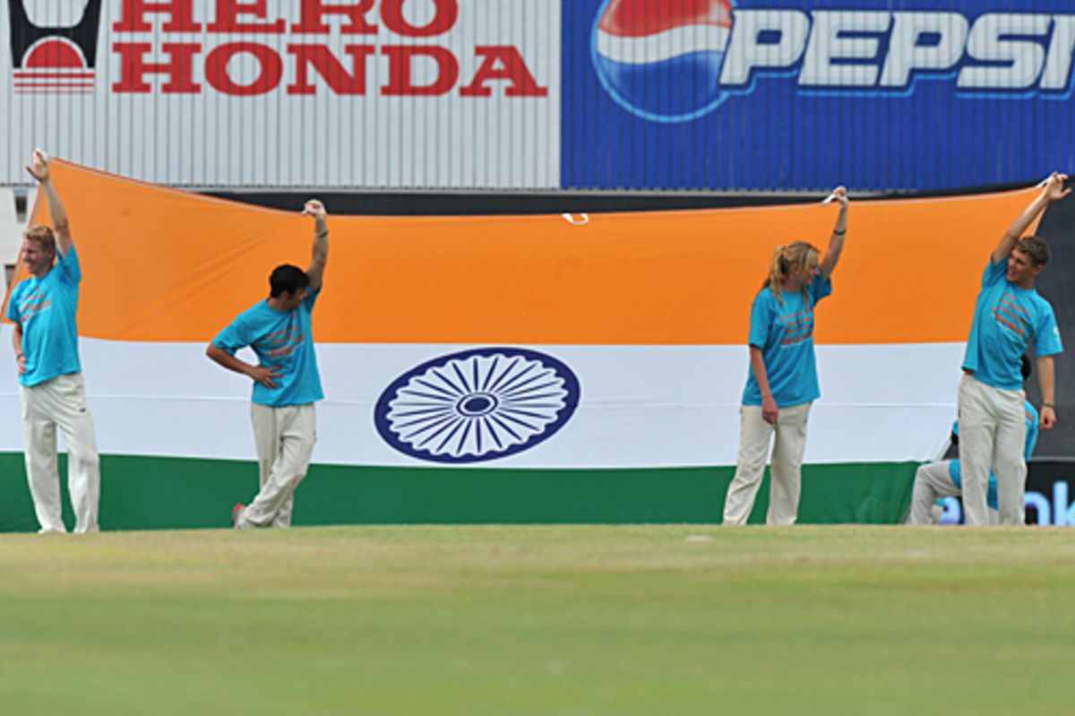 Volunteers hold up the Indian flag ahead of the national anthems ...