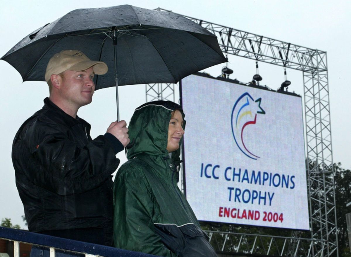 Two spectators shelter under an umbrella | ESPNcricinfo.com
