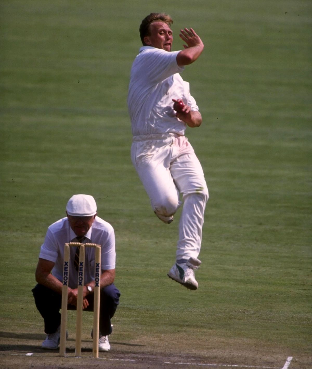 Fast bowler Brett Schultz bowls, watched by umpire Cyril Mitchley ...
