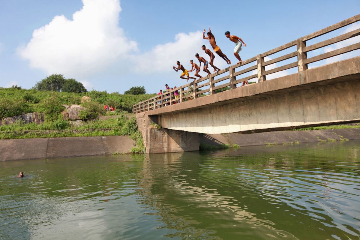 Children dive from a bridge into a river to cool off | ESPNcricinfo.com