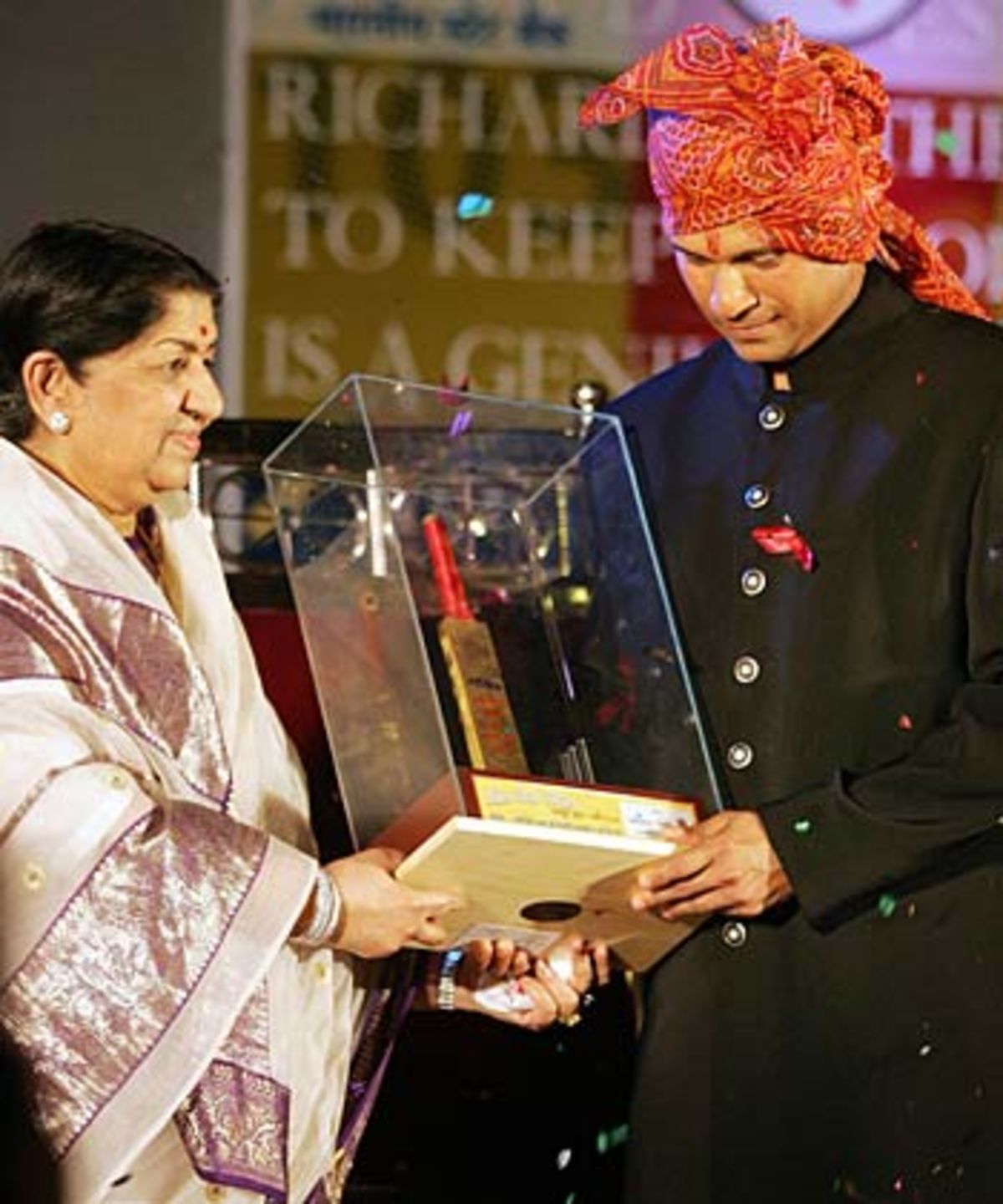 Sachin Tendulkar is presented with a minauture cricket bat made of gold ...