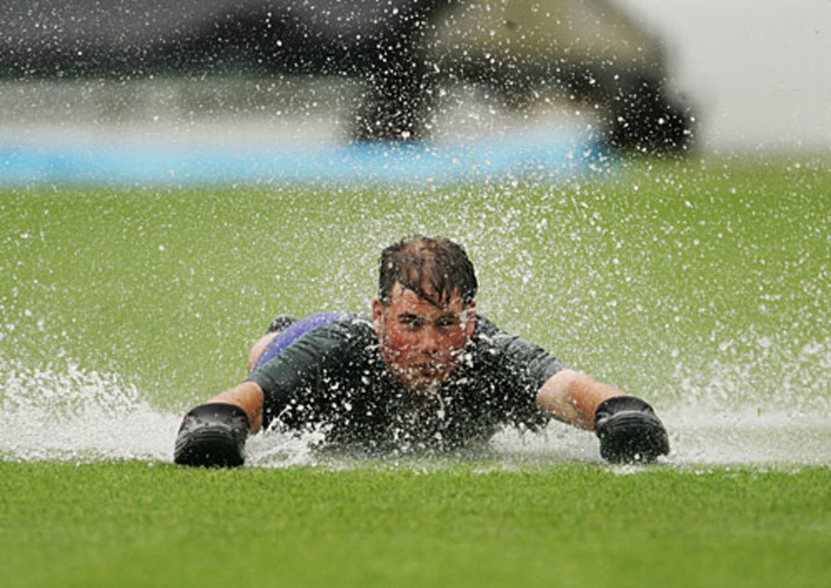 A groundsman dives on the waterlogged outfield at Seddon Park ...