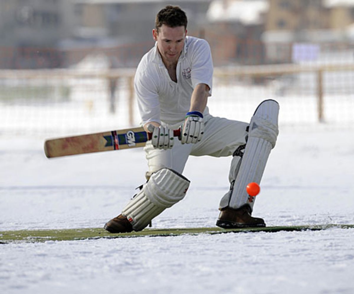 Players roll out a cricket pitch carpet to play on the ice ...