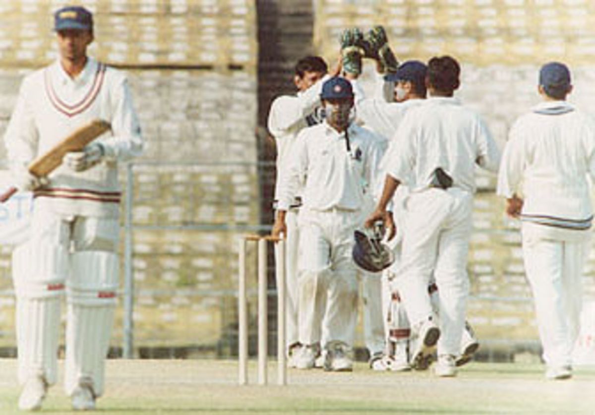 Utpal Chatterjee taking a look at MS Dhoni's bat in between the overs ...