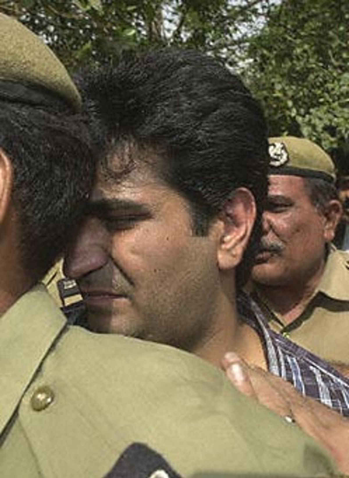 Suspected bookmaker Kishan Kumar hides behind police officers ... Suspected bookmaker Kishan Kumar hides behind police officers ...