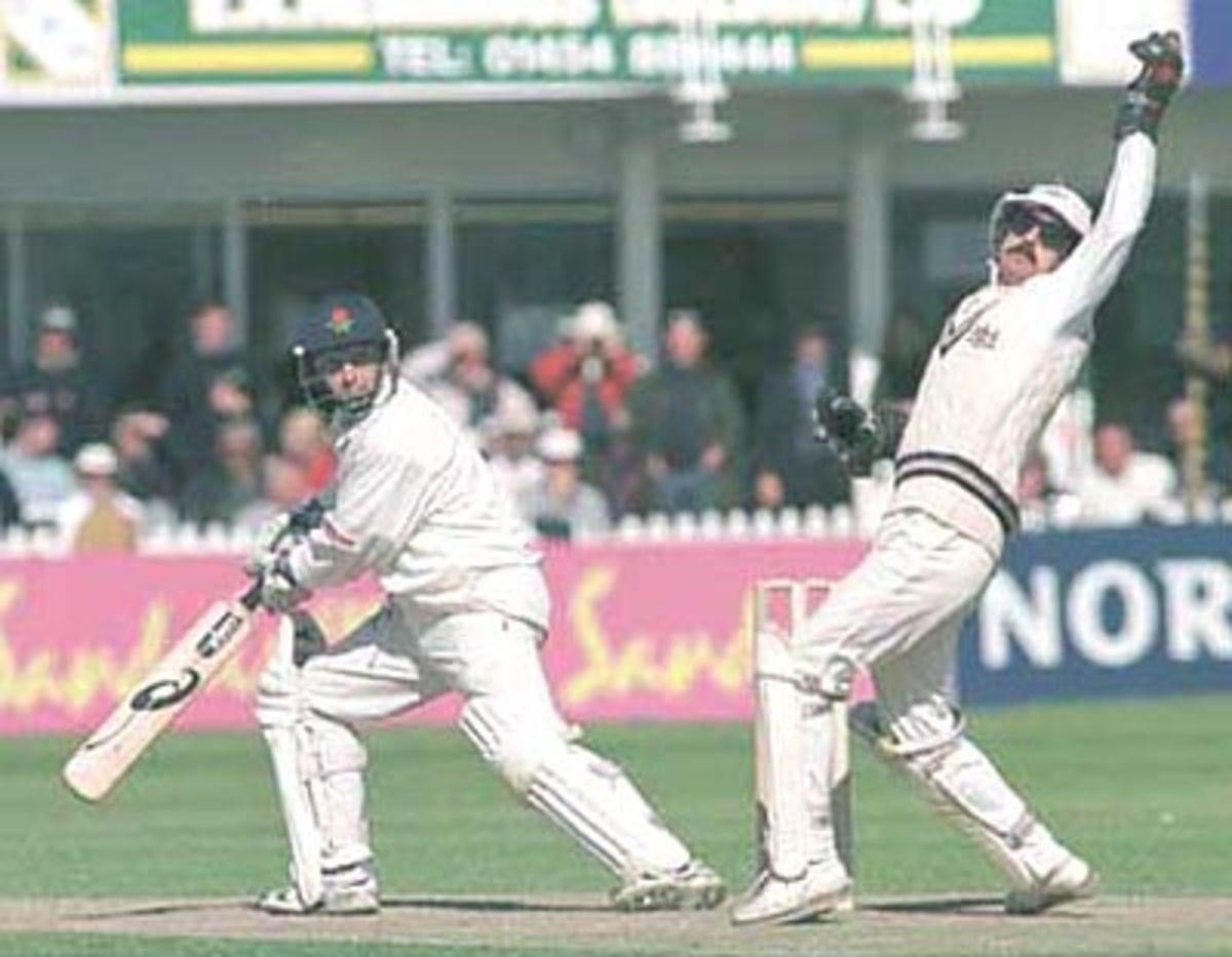Neil Fairbrother looks on as the ball races past the wicketkeeper ...