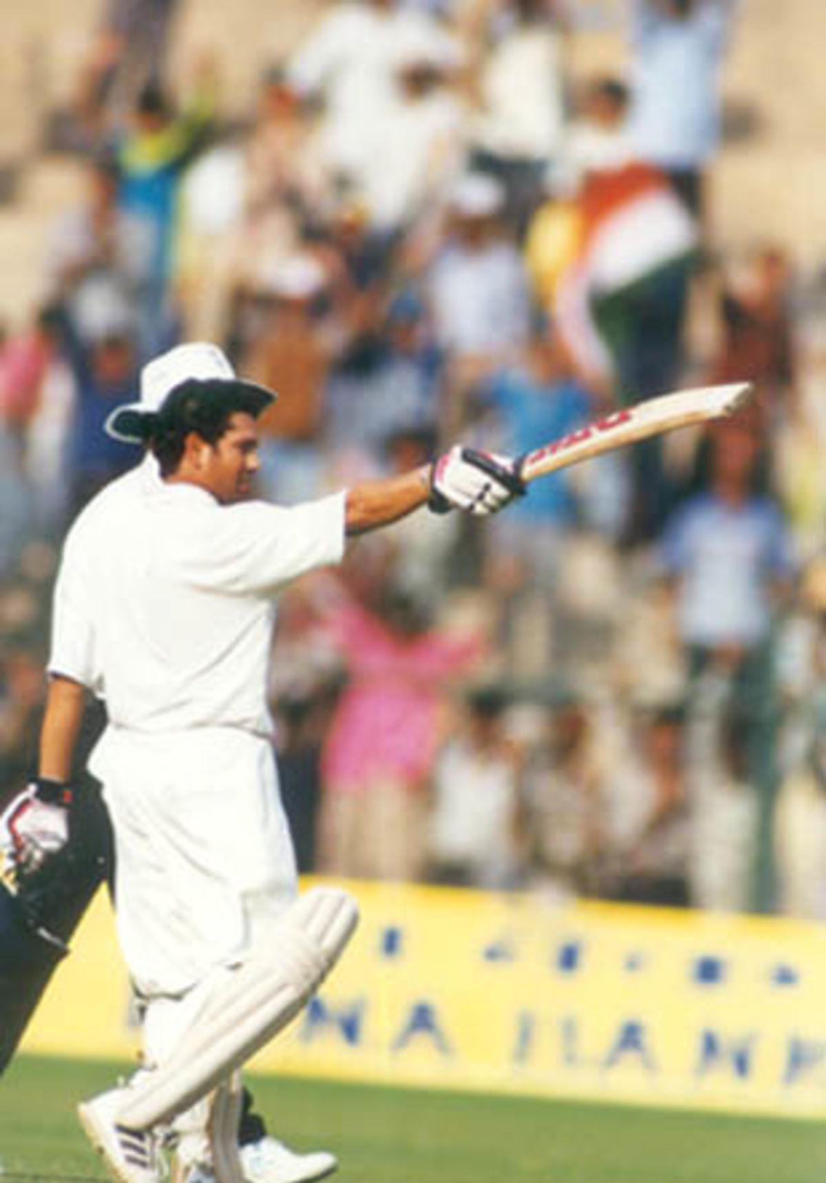Raising his bat to the crowd after completing his Century ...