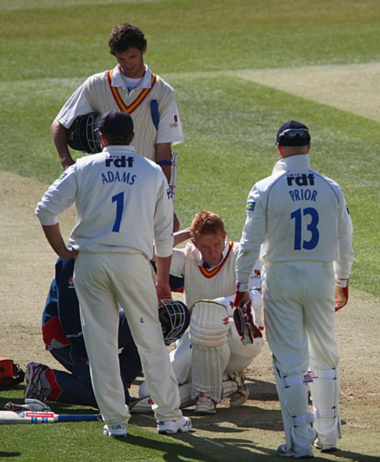 Concerned players hover over Steve Kirby after he was smacked on the ...