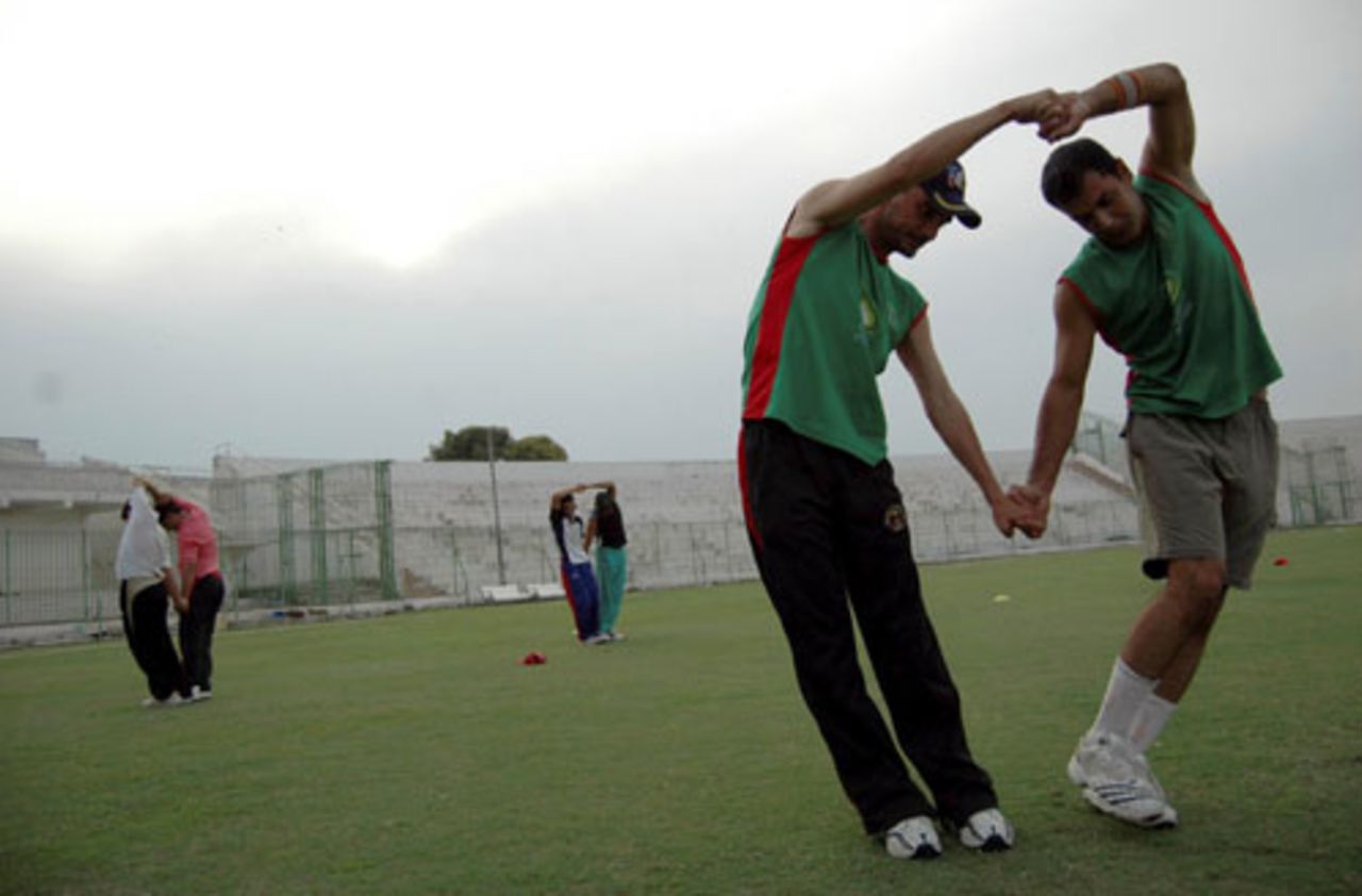 Afghan cricket players stretch during their training session in ...