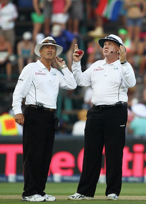 Umpires Steve Davis and Tony Hill look worriedly up into the heavens ...