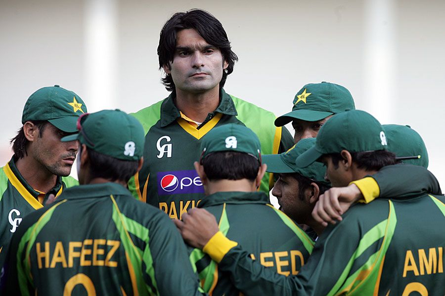 The Pakistan players huddle together during a break in play ...