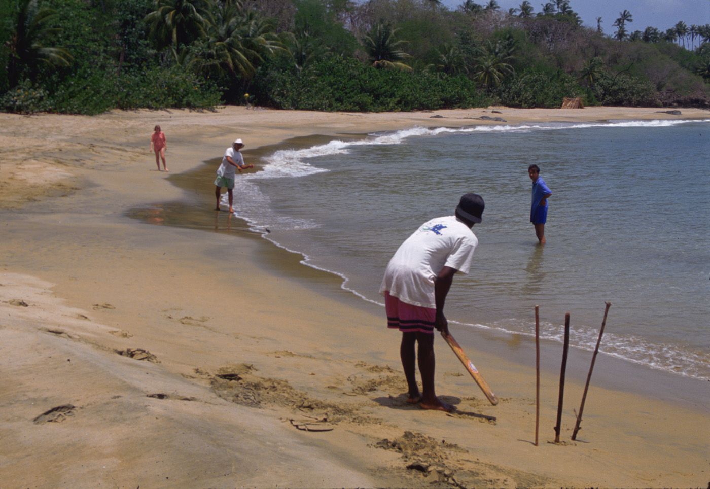 A game of cricket by the water's edge on a beach in Tobago ...