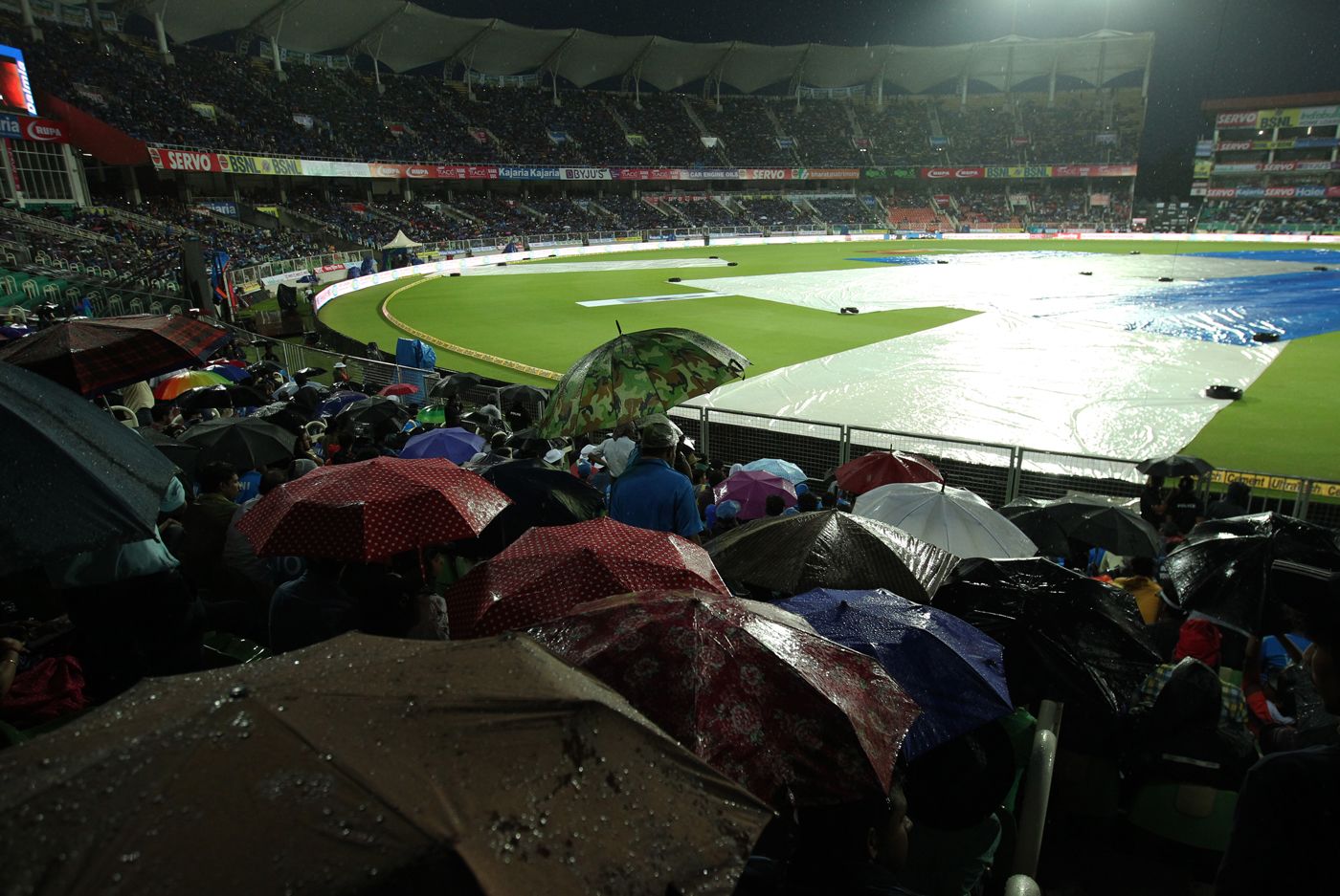 Spectators and the Greenfield Stadium pitch take cover from the rain ...