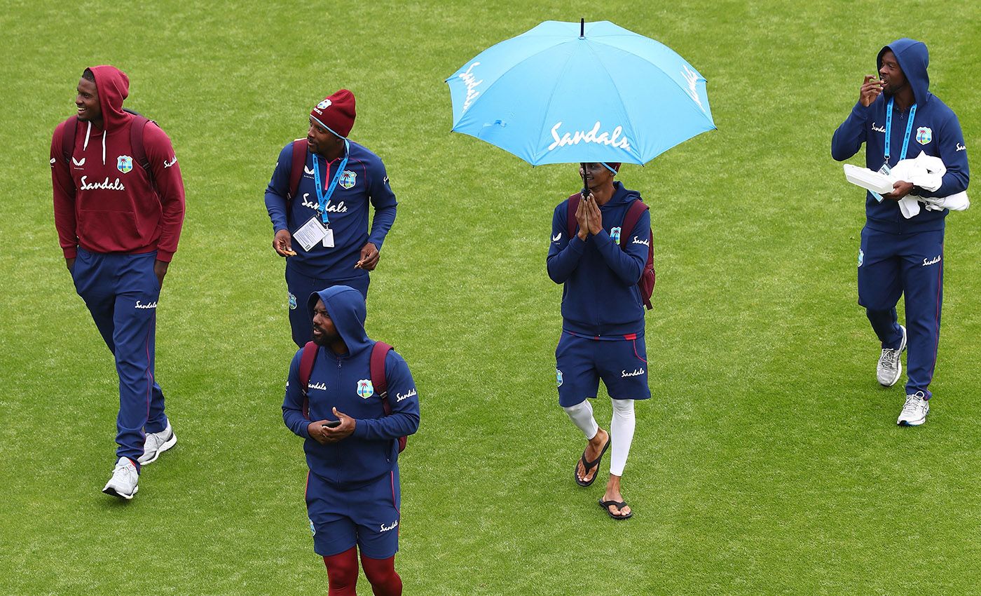 Jason Holder walks on a sodden outfield with Kemar Roach, Shamarh ...