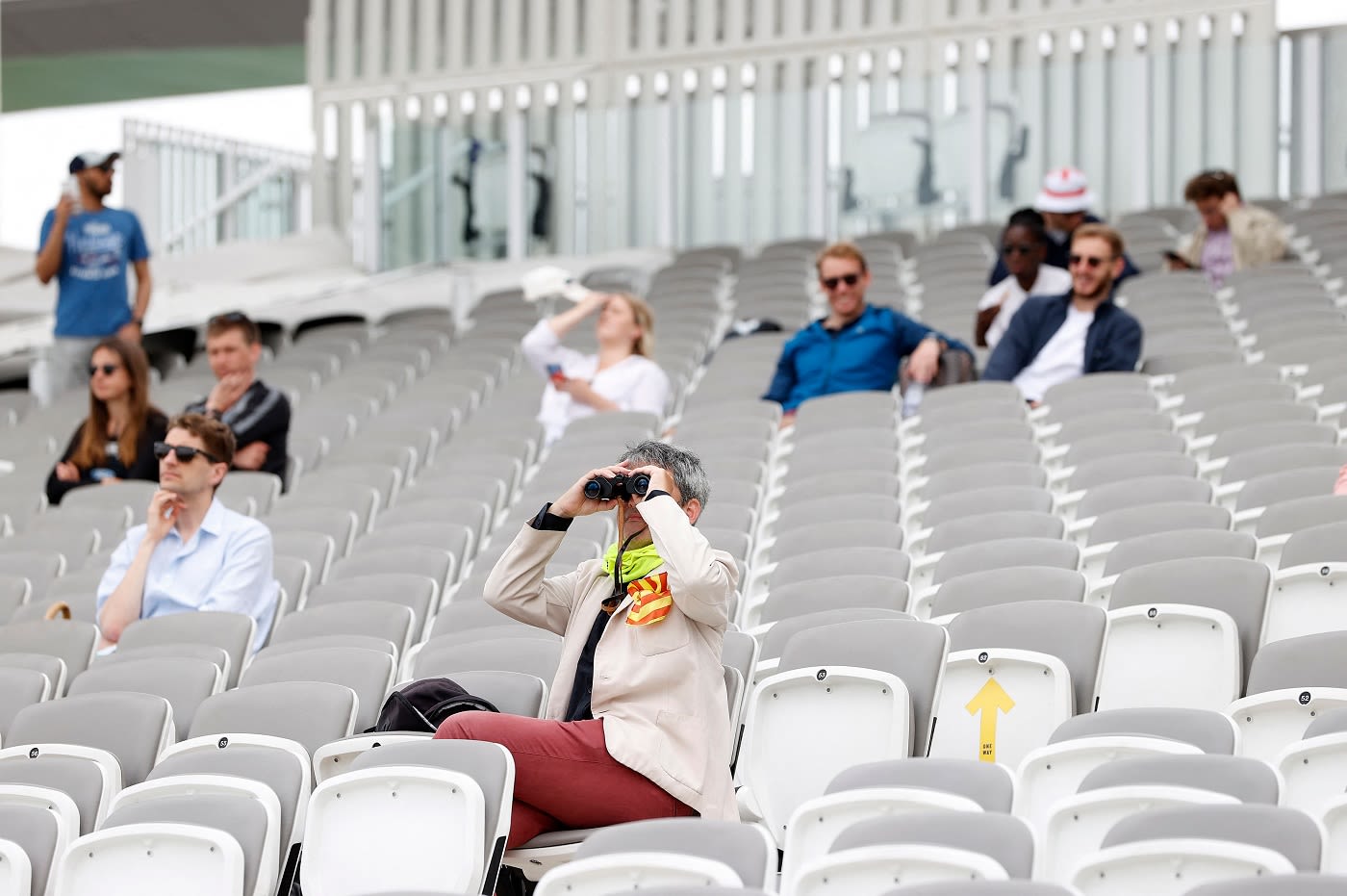 Spectators sit socially distanced as they watch the play on the fifth ...