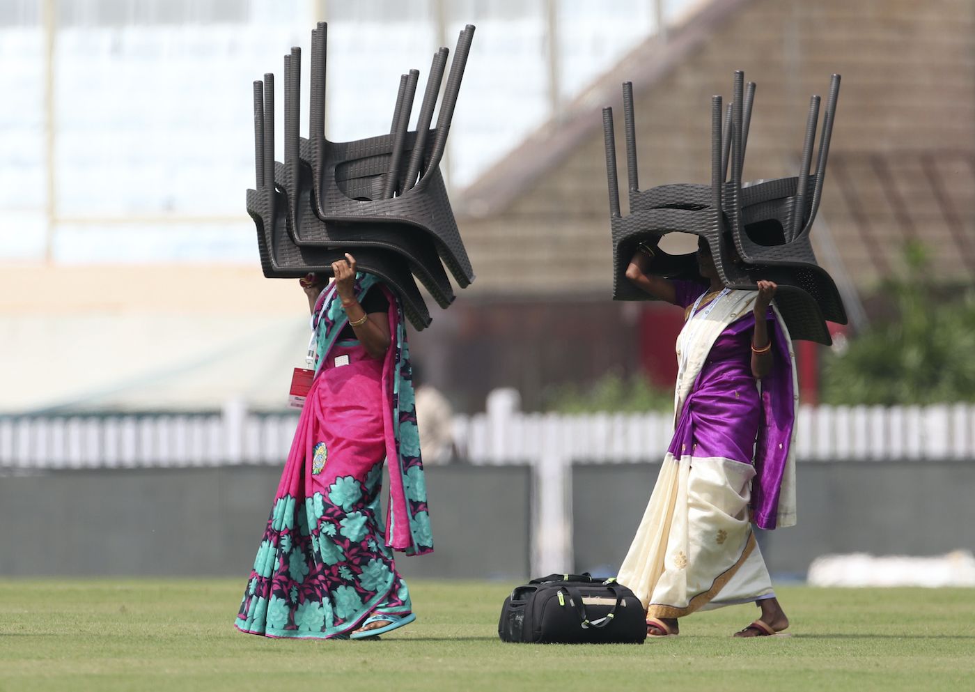 Women workers carry chairs into the field during a training session ...