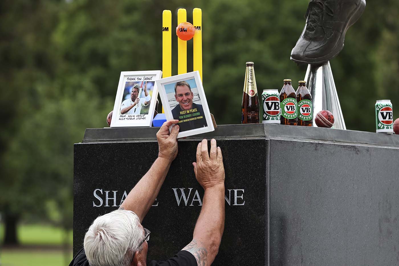 A man places a set of stumps at Shane Warne's statue at the MCG ...