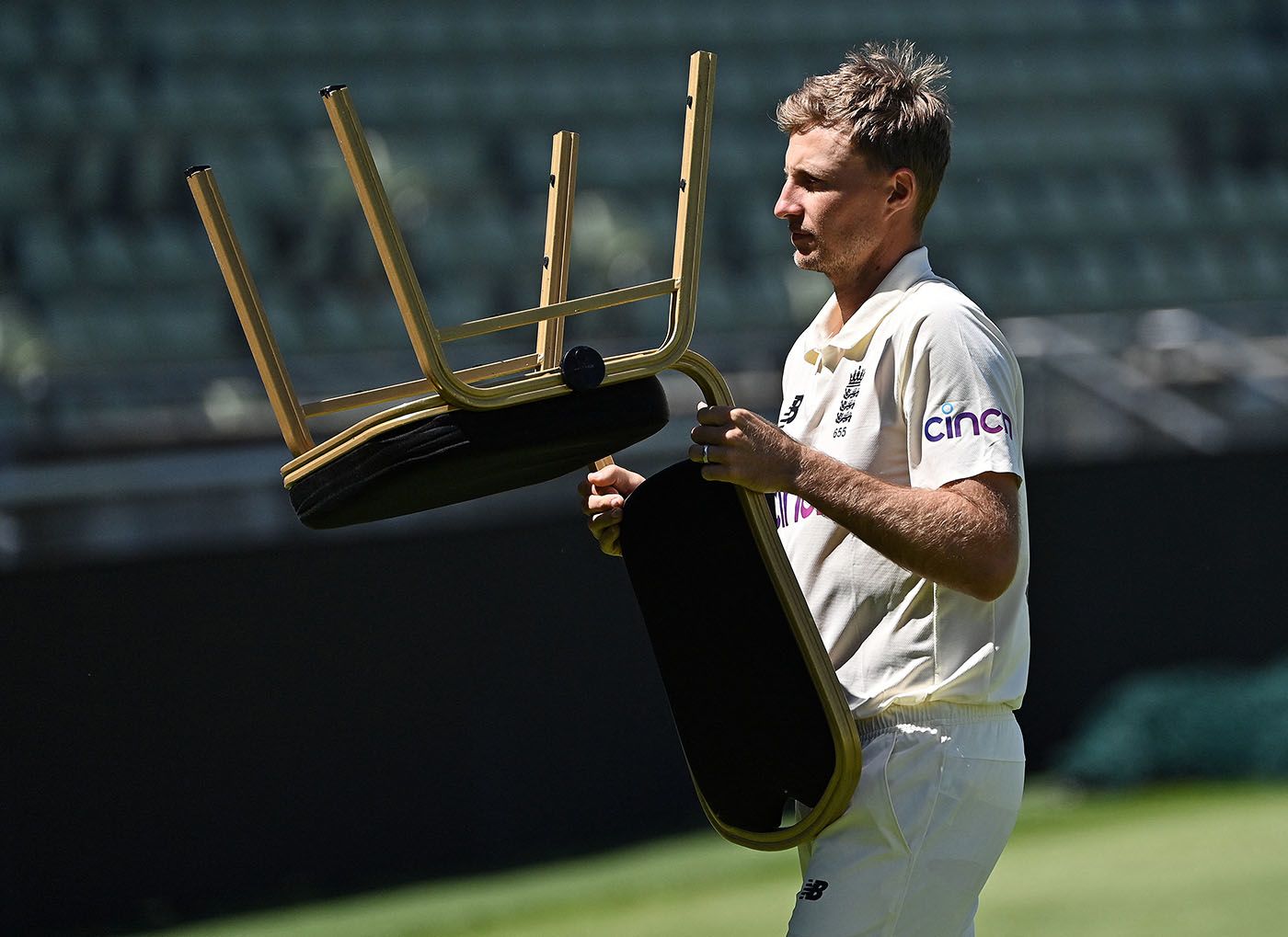 Joe Root carries his chair off the pitch after posing for a team photo ...