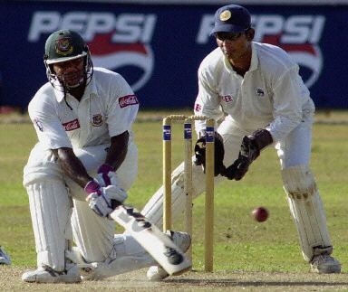 Bangladeshi batsman Aminul Islam sweeps a ball as Sangakkara looks on ...