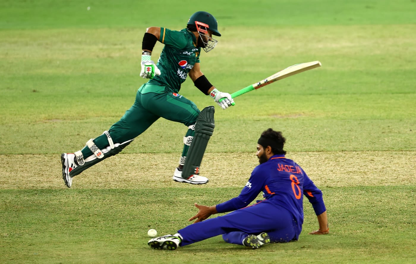 Ravindra Jadeja swoops down on the ball as Mohammad Rizwan runs towards ...
