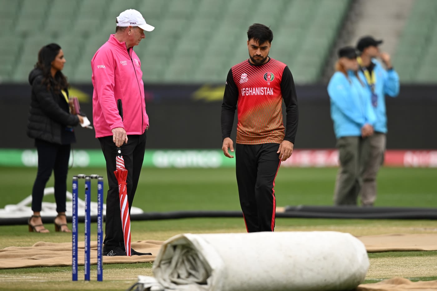 Rashid Khan and reserve umpire Paul Reiffel have a look at the pitch ...