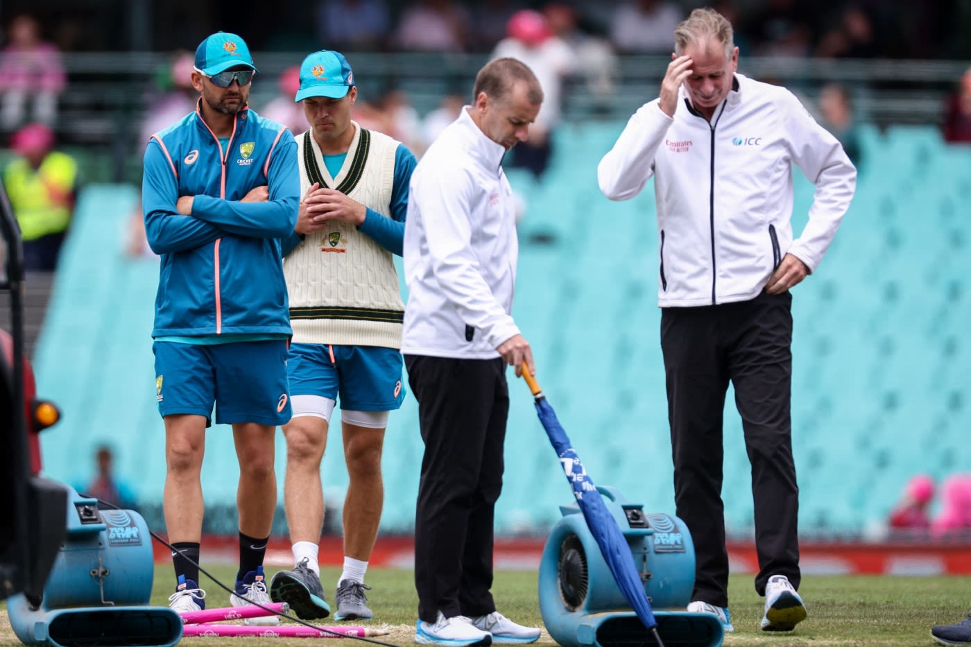 Umpires Chris Gaffaney and Paul Reiffel inspect the wet areas around ...
