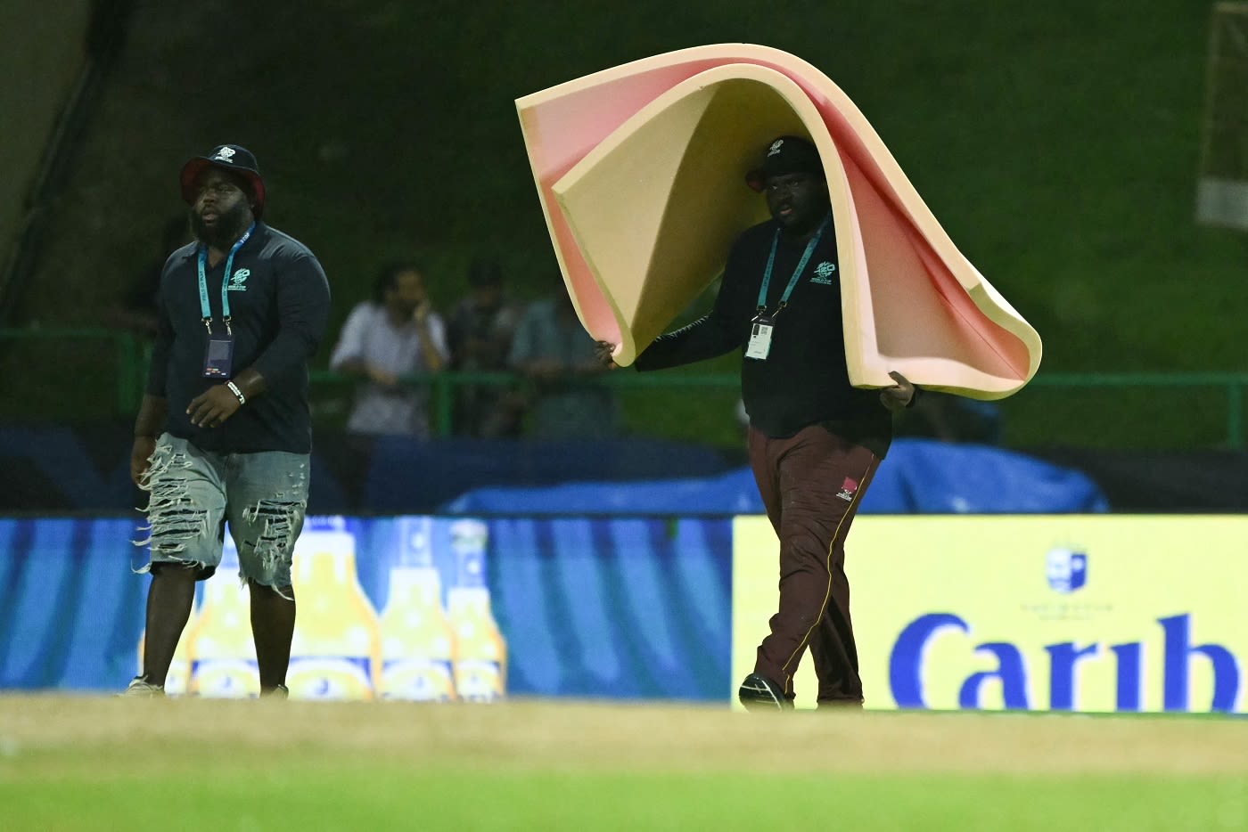 A ground staff brings sponges to soak up water from the field ...