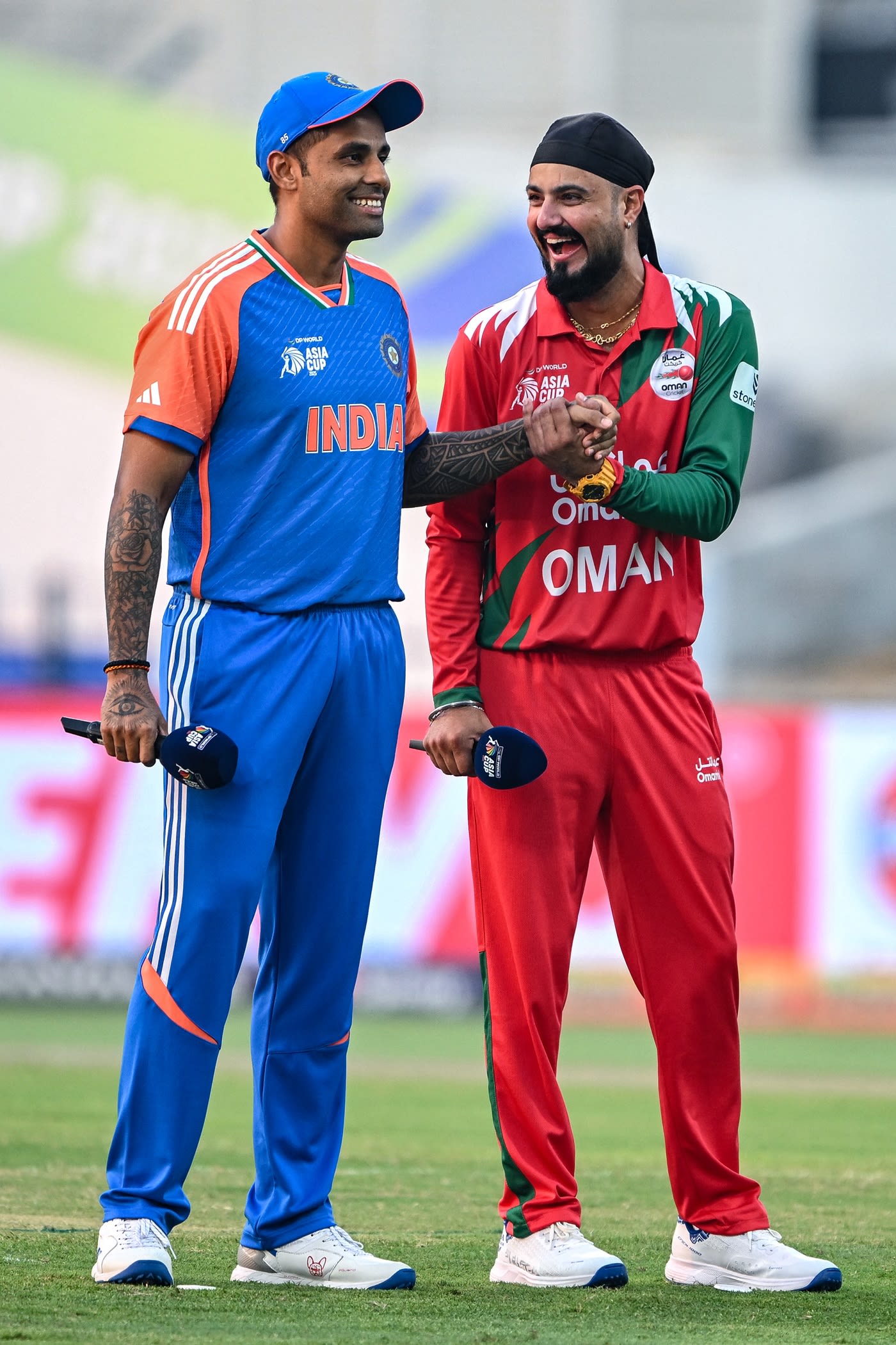 Oman captain Jatinder Singh shares a light moment with India captain Suryakumar Yadav at the ...