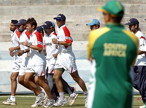 Indian cricketers jog around the ground as a South African player looks ...