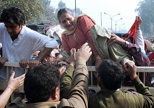 An elderly woman is helped over the border | ESPNcricinfo.com