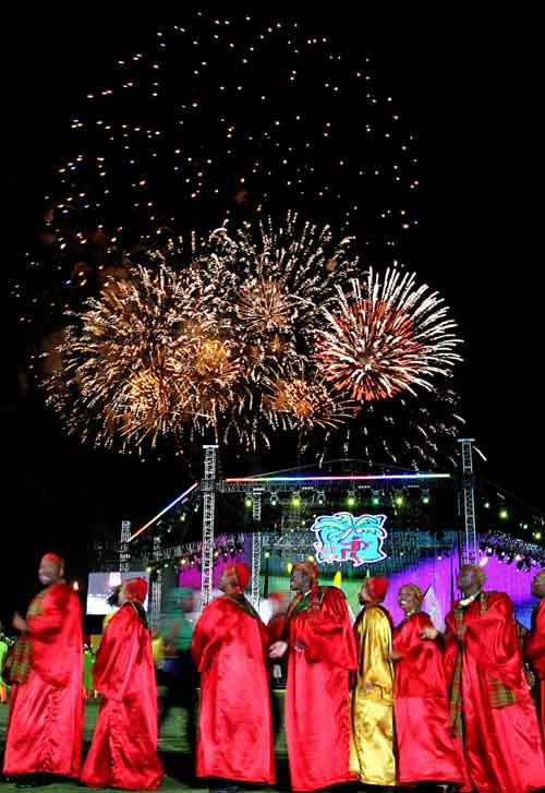 Dancers perform as fireworks illuminate the night sky during the ...