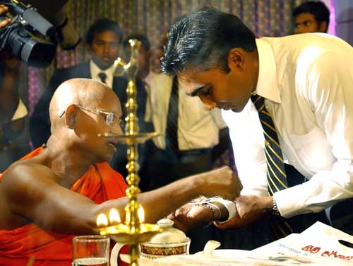 A Buddhist monk ties a blessed white thread around the wrist of captain ...