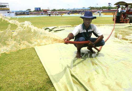 A member of the ground staff pumps out water from the field ...