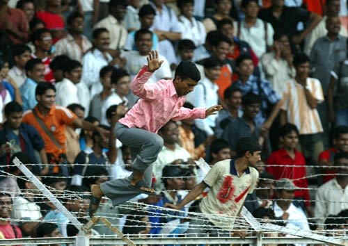 A Indian fan clears a barbed-wire fence to get a closer look at the ...