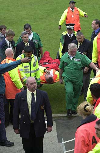 An injured security guard is carried from the Leeds pitch after being ...