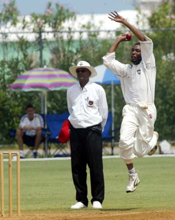 Austin Codrington (Canada) in delivery stride. Umpire is Steve Kalloo ...