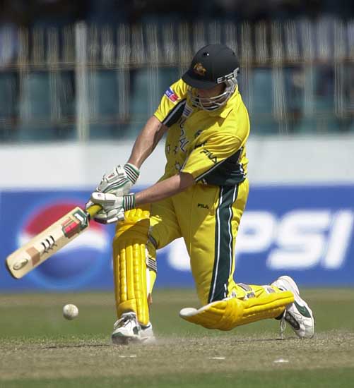 Adam Gilchrist gets down to sweep the ball in his half century ...