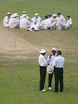 England players sit on the outfield and wait following a power cut ...