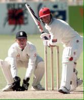 South Australian opener Martin Faull drives, Alec Stewart looks on ...